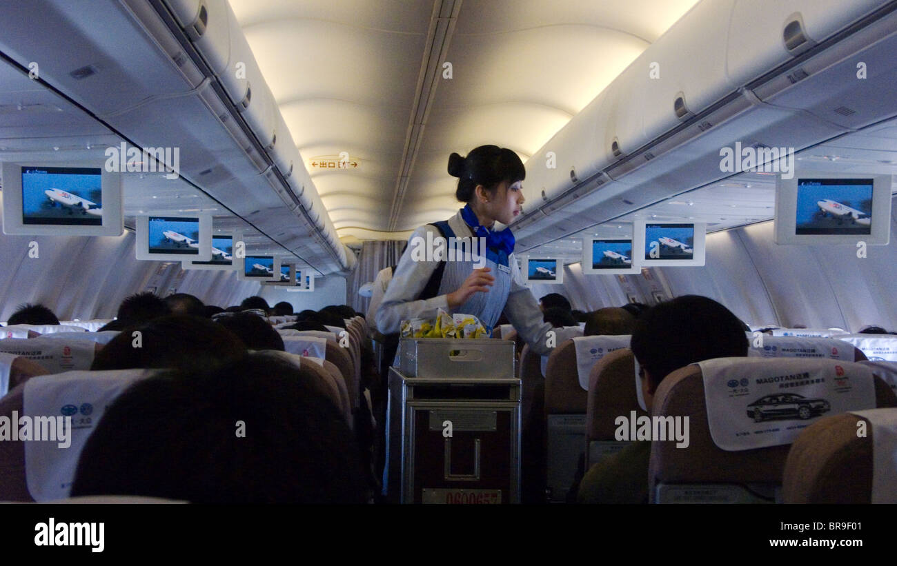 A flight attendant on eastern China Airlines serves passengers on a ...
