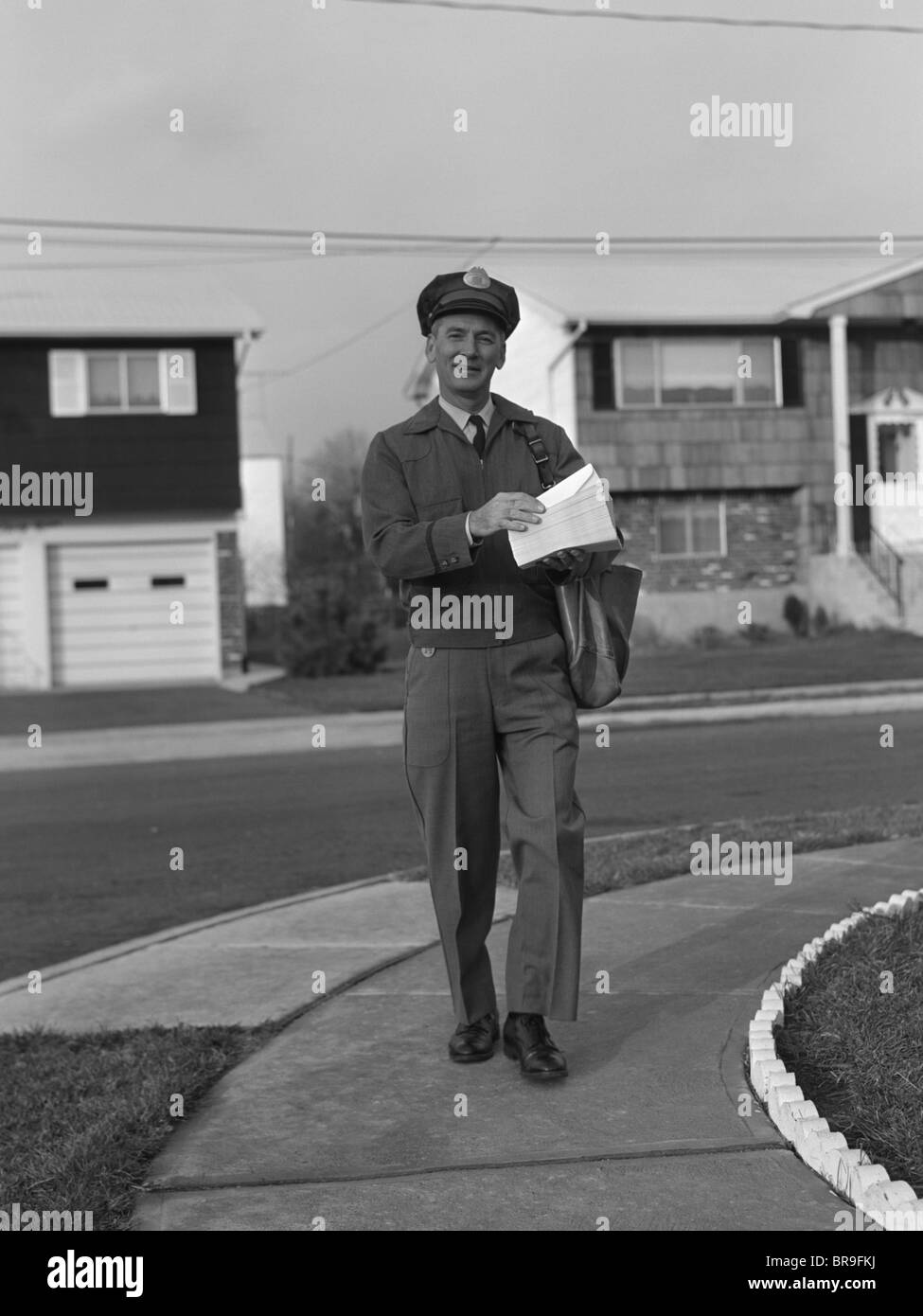 1950s 1960s MAILMAN WALKING OUTSIDE CARRYING MAIL LOOKING AT CAMERA ...