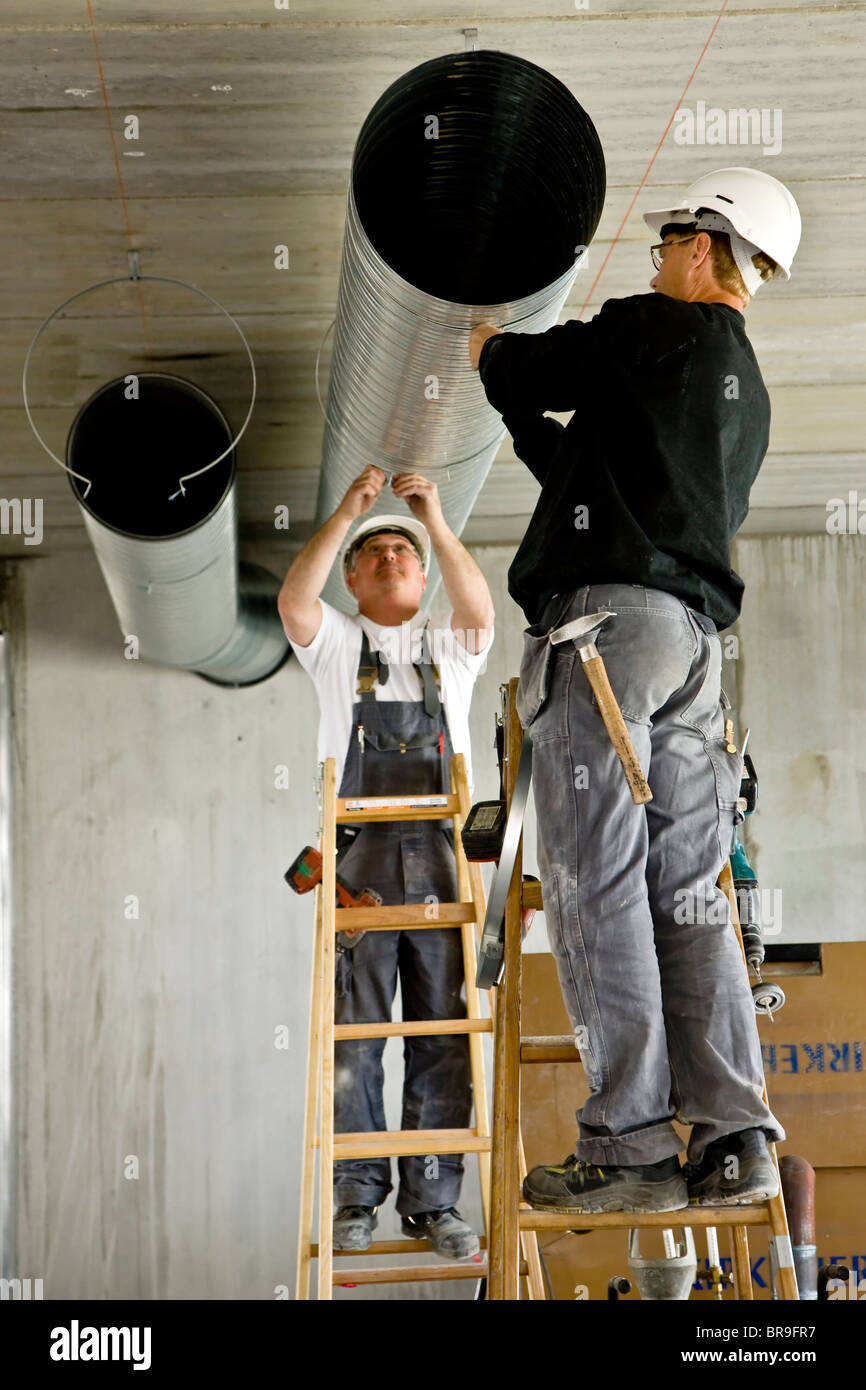 Two ventilation fitters installing a ventilation pipe Stock Photo - Alamy