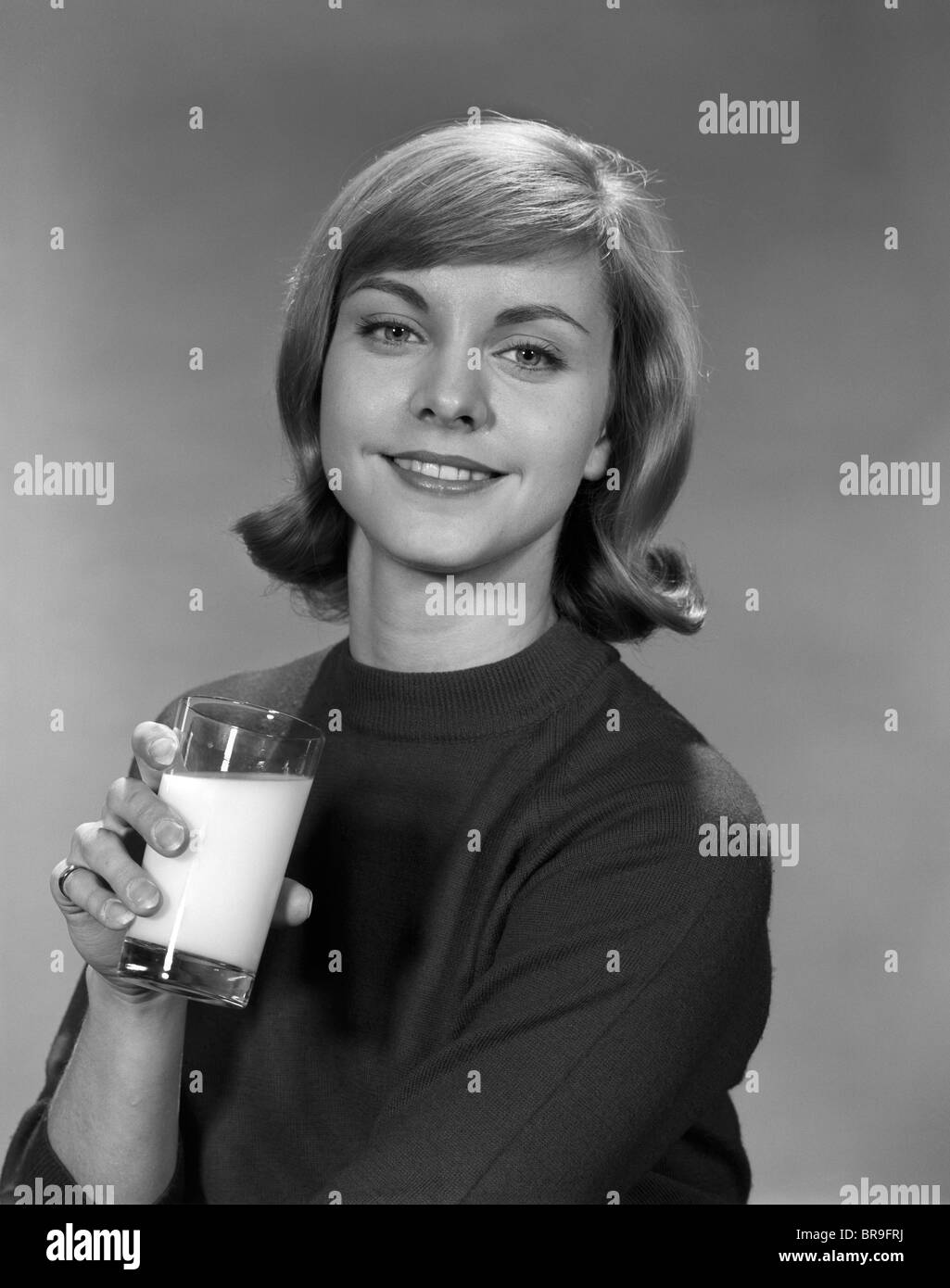 1960s PORTRAIT YOUNG SMILING WOMAN HOLDING A GLASS OF MILK LOOKING AT ...
