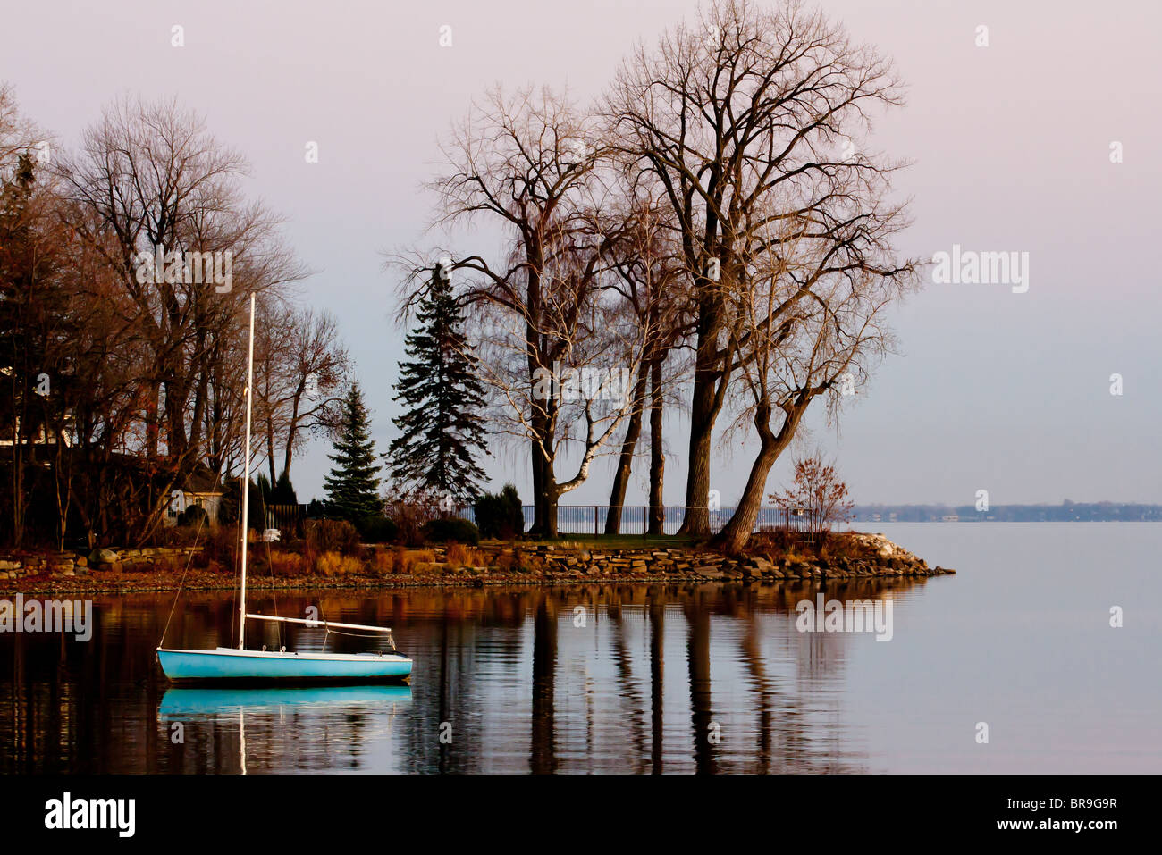 A small, blue sailboat is anchored on Lac Saint-Louis in Quebec Stock ...