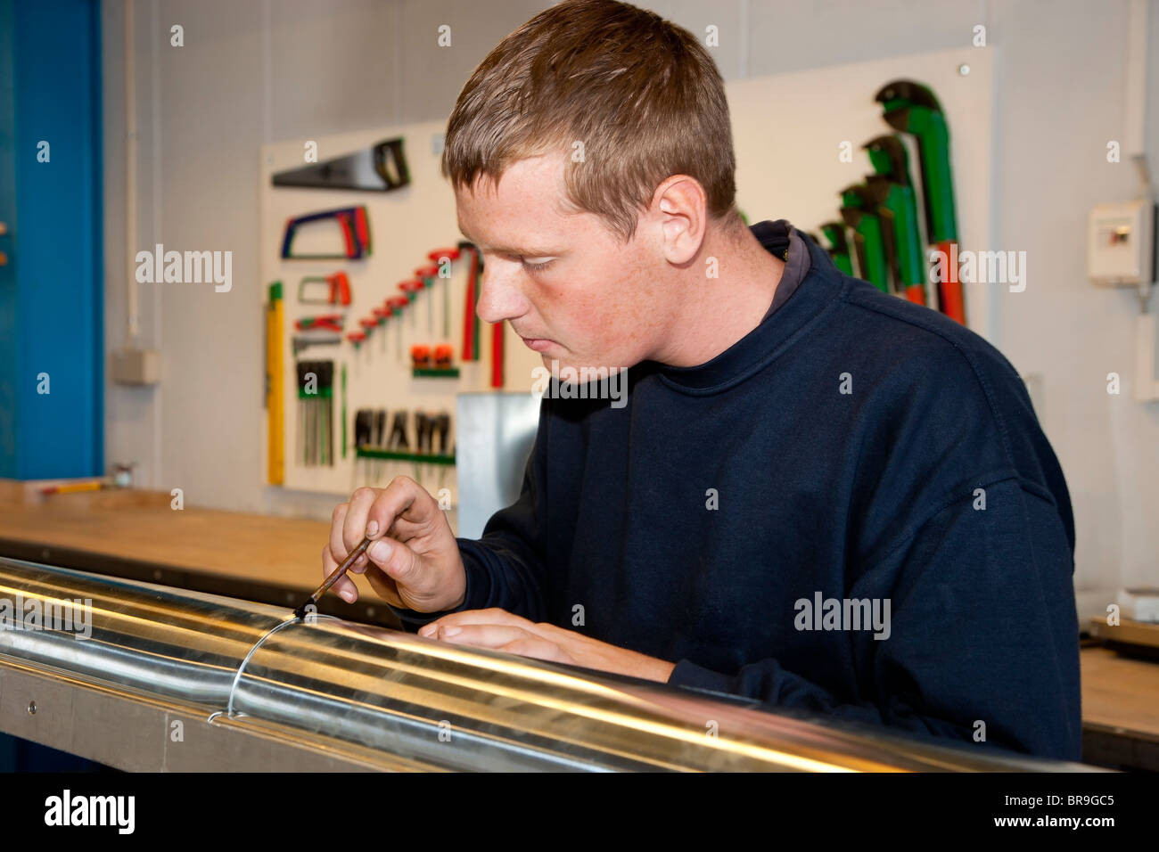 Young plumber making a gutter at the workshop Stock Photo - Alamy
