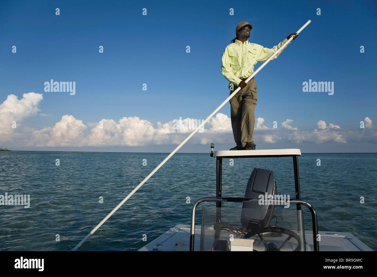Bonefishing guide poles his boat in shallow waters near Andros Island ...
