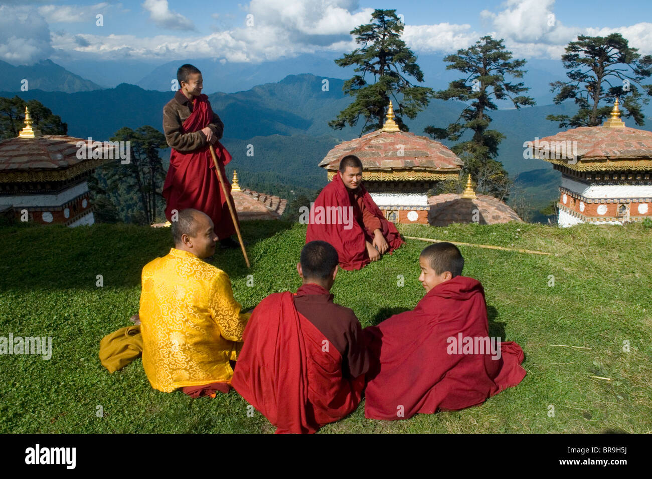 A group of five monks sit together overlooking the mountains of Bhutan ...