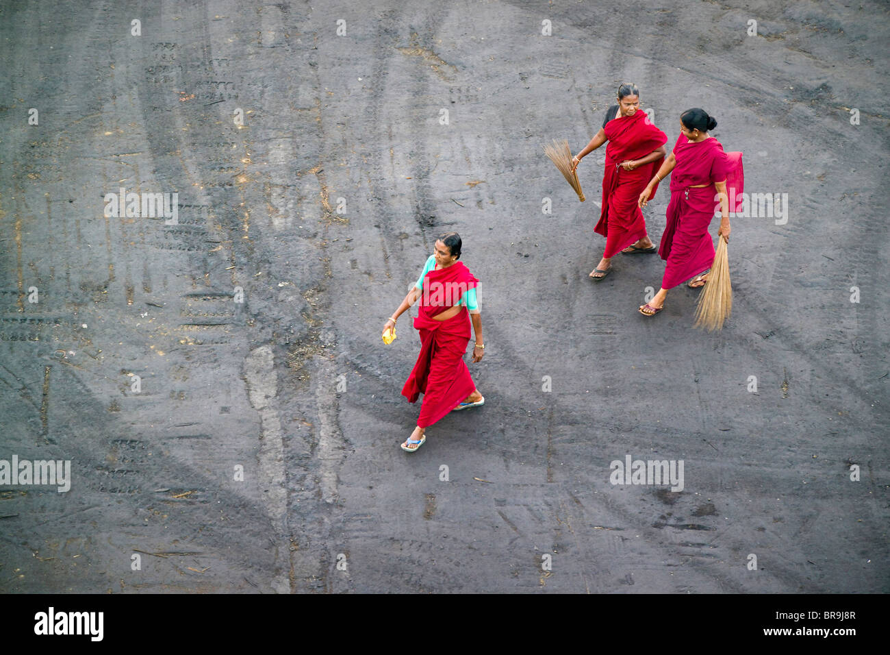 Three sari clad women prepare to sweep the docks in Chennai Port ...