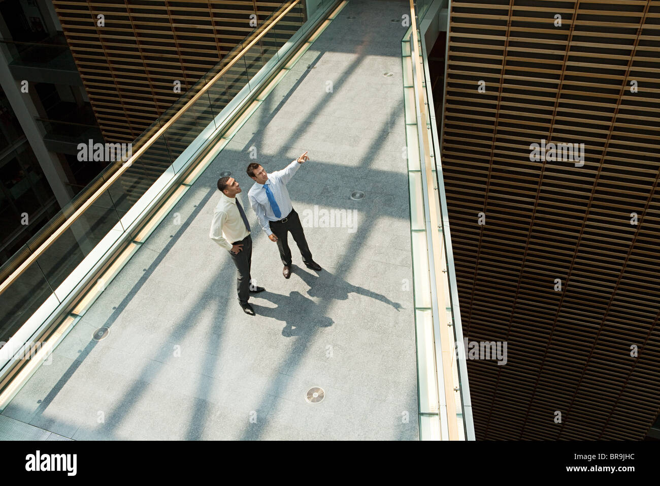 Businessmen on office walkway Stock Photo - Alamy