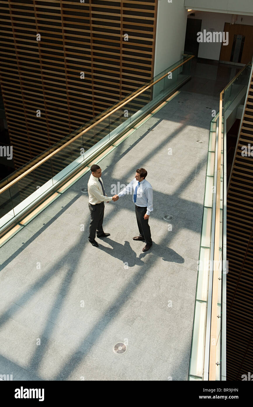 Businessmen shaking hands on office walkway Stock Photo - Alamy