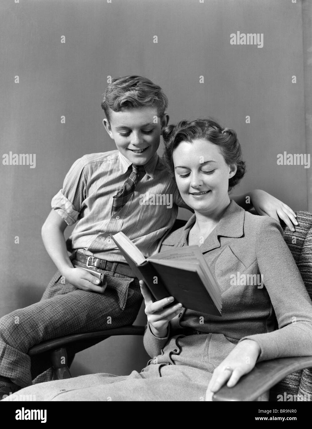 1940s BOY AND WOMAN SITTING CHAIR READING BOOK Stock Photo - Alamy