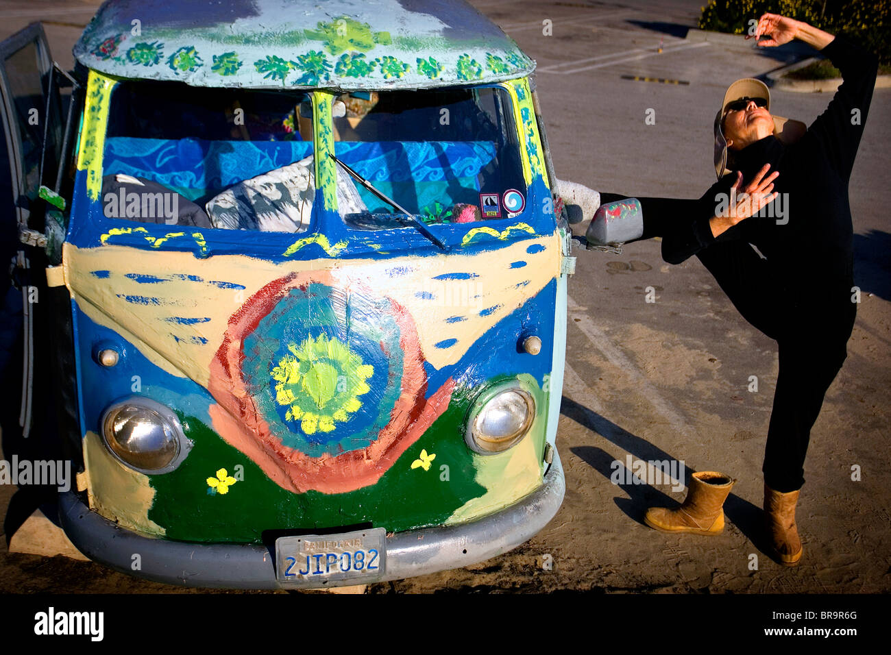 Woman stretches next to her flower-painted VW bus she calls home in ...