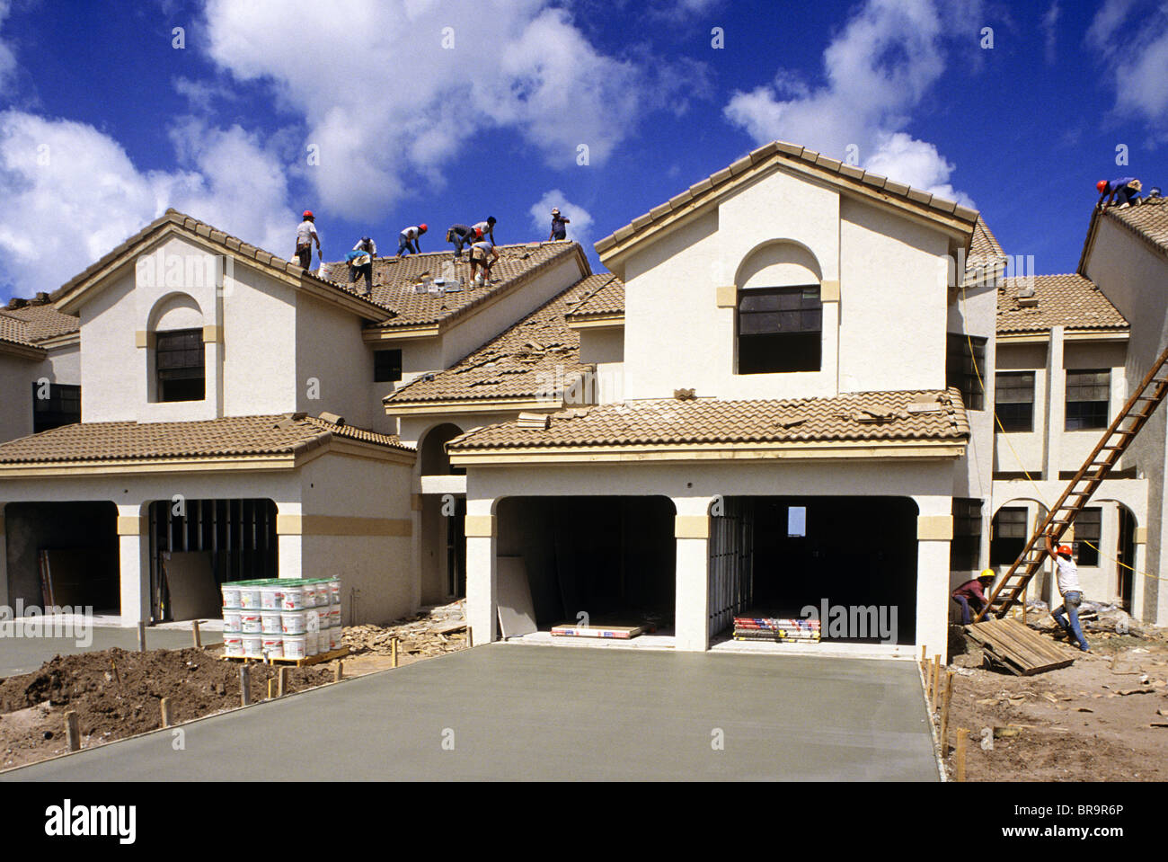 1990s CONSTRUCTION SITE WORKERS PUTTING TILE ROOF ON STUCCO TOWNHOUSES ...