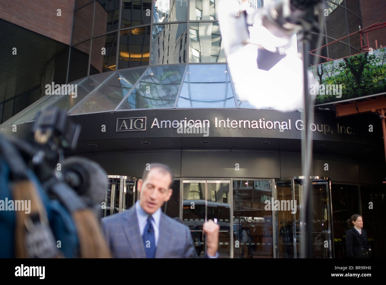 A male news anchor stands in front of AIG's headquarters in New York ...