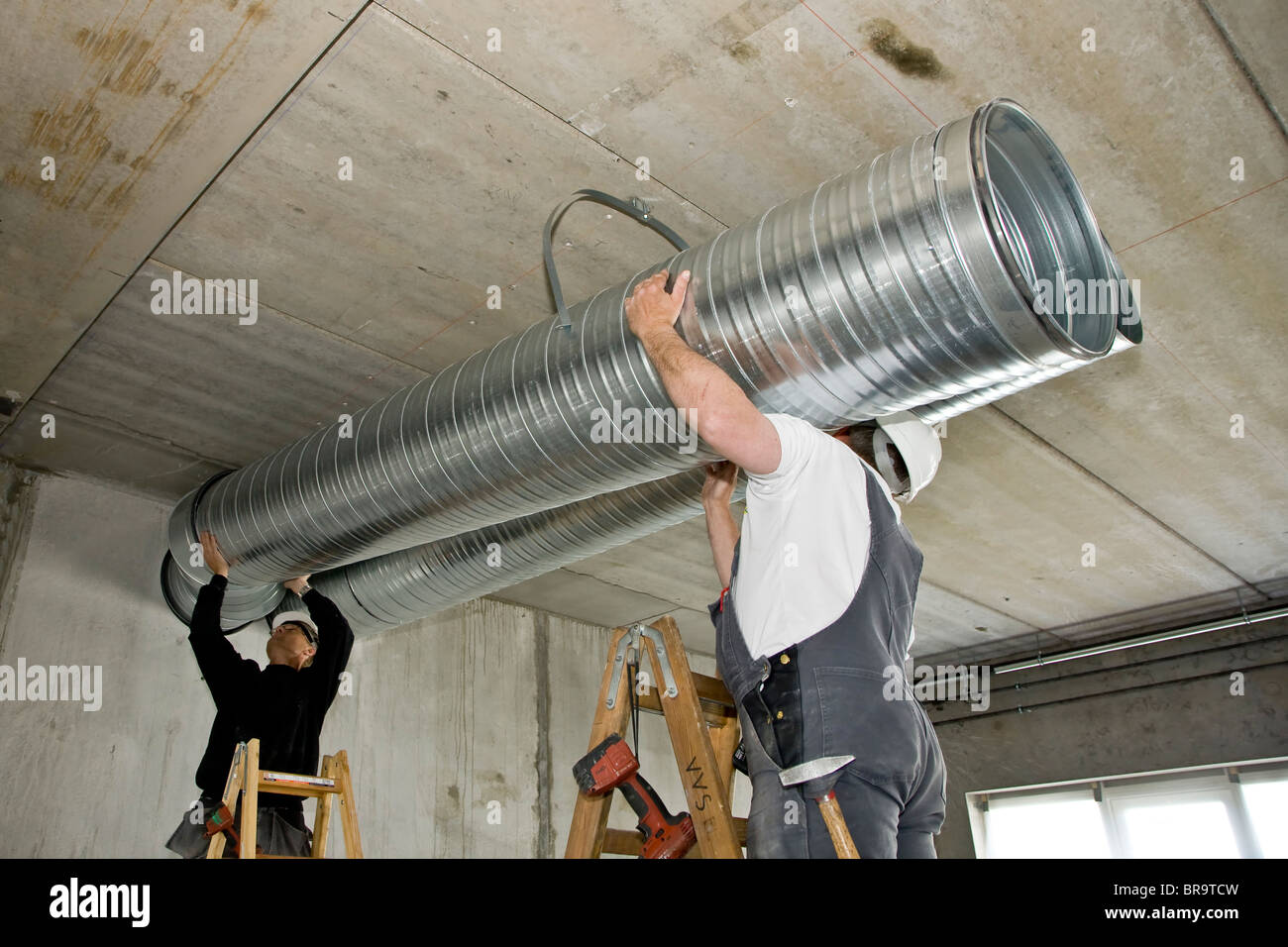 Two ventilation fitters installing a ventilation pipe Stock Photo - Alamy