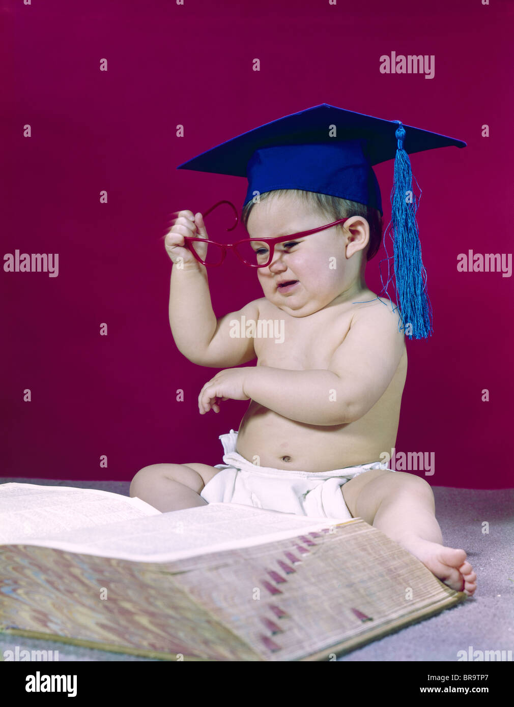 1960s GRADUATE BABY WEARING MORTARBOARD EYEGLASSES READING BOOK Stock ...