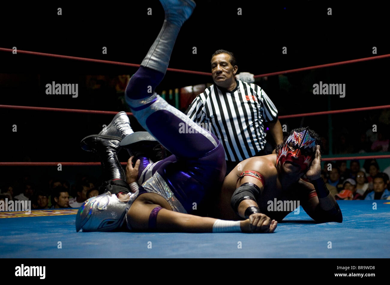 Lucha Libre wrestlers fight as the referee looks on during a Lucha ...