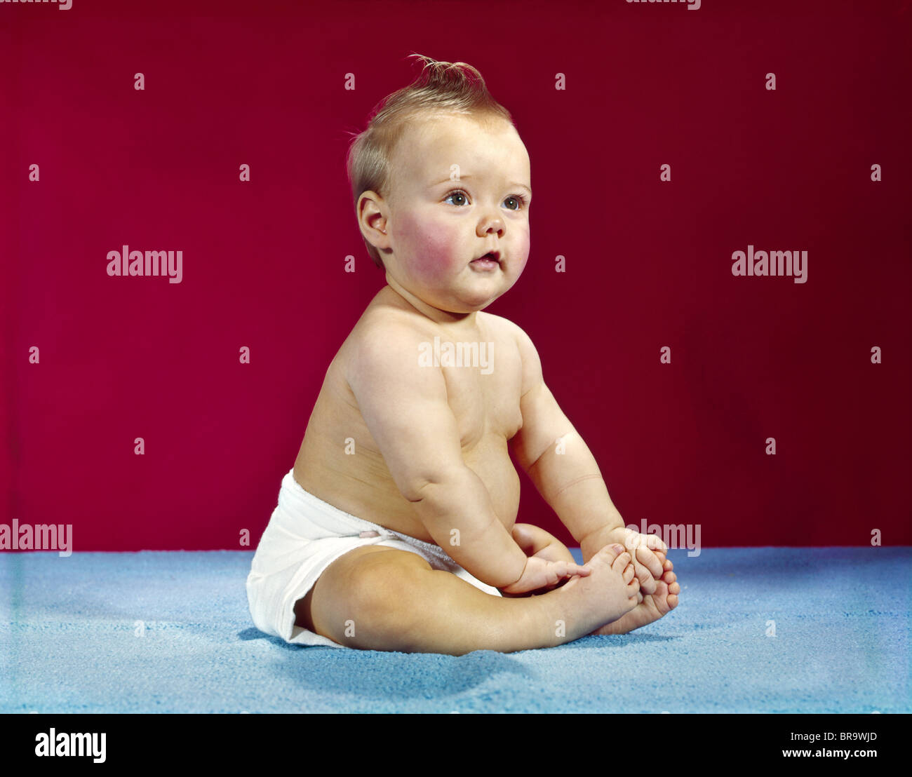 1960s BABY IN DIAPER SITTING UP AGAINST RED BACKGROUND Stock Photo - Alamy
