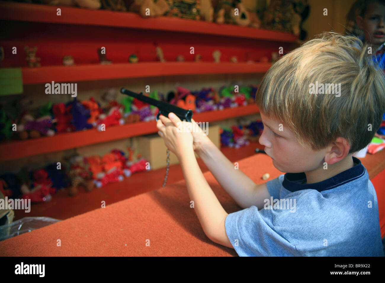 Boy shooting with a pistol in an arcade game at Challock Goose Fair ...