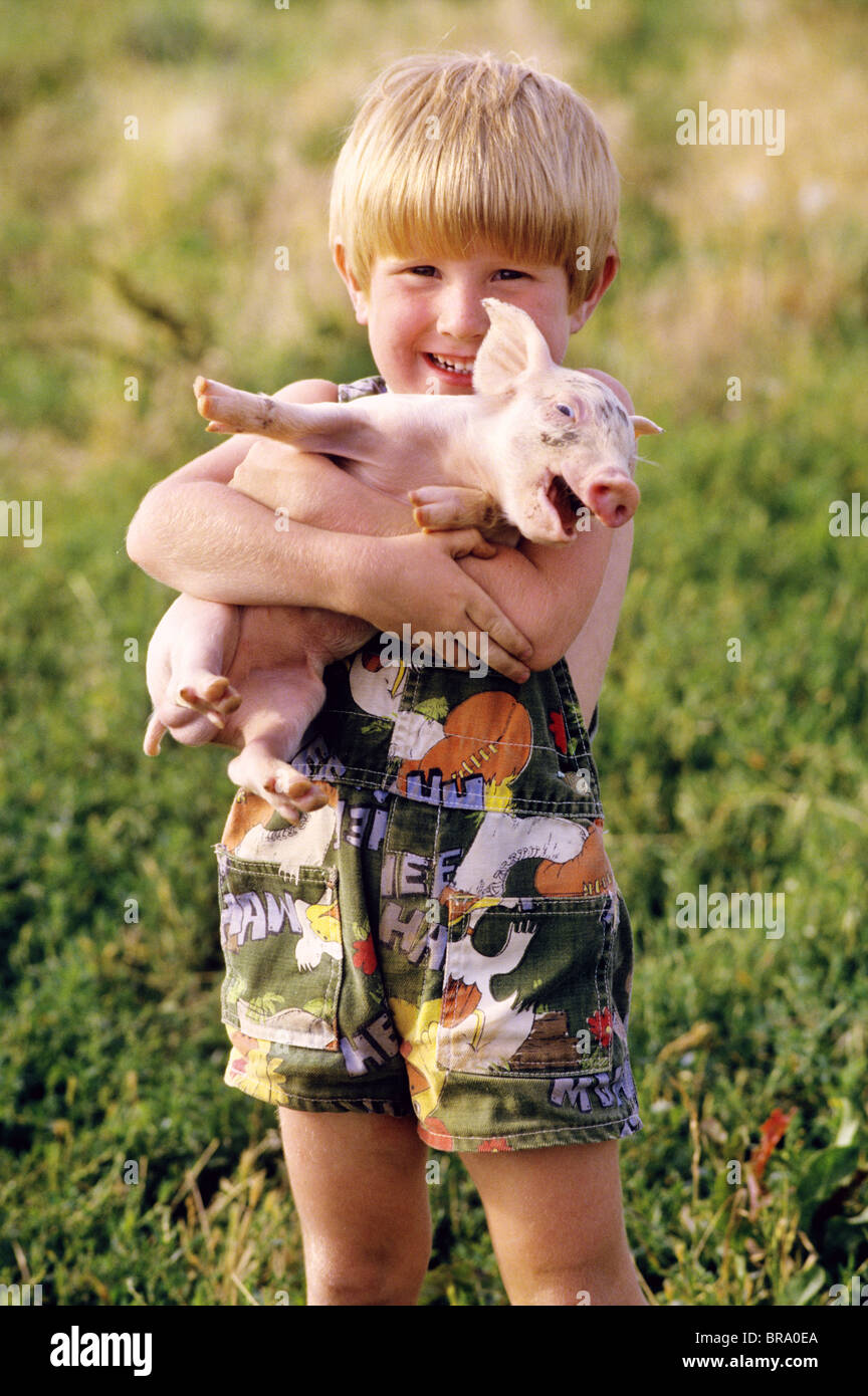 SMILING BLOND 4 YEAR OLD BOY HOLDING SQUEALING BABY PIG Stock Photo - Alamy