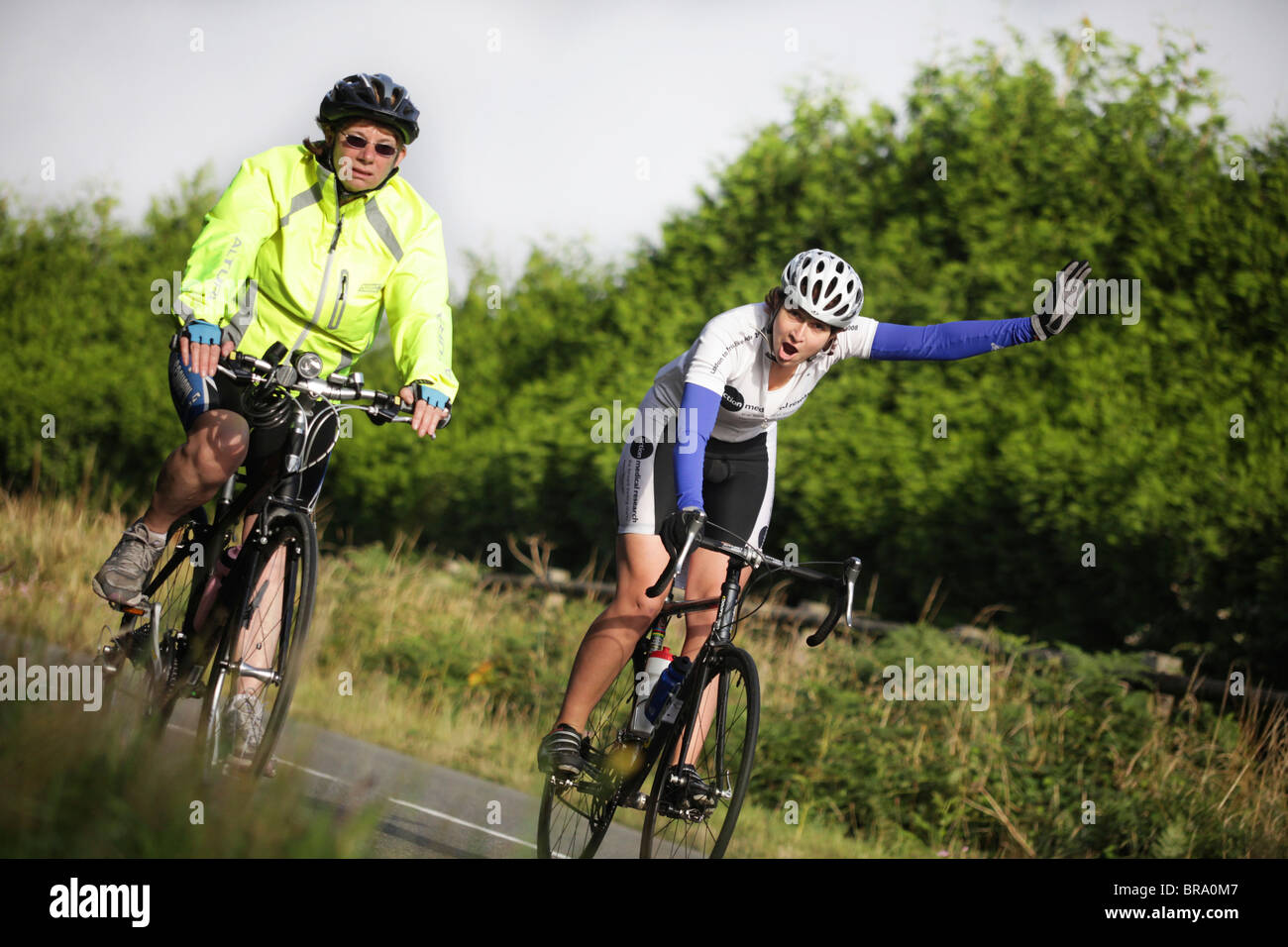 Two women in full cycling gear road biking. One woman cheering Stock ...