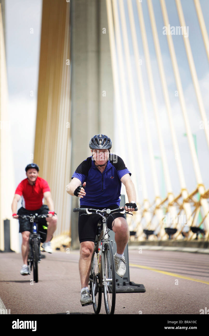Two men cycling across a bridge in France one man giving the thumbs up ...