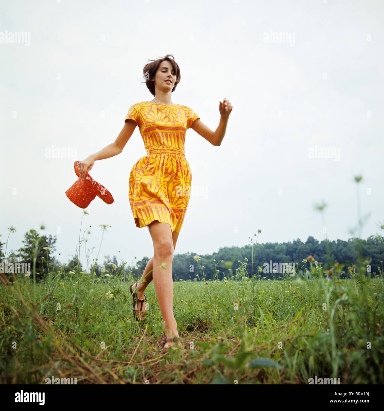 1970s YOUNG WOMAN WEARING COLORFUL PRINT DRESS RUNNING IN FIELD ...