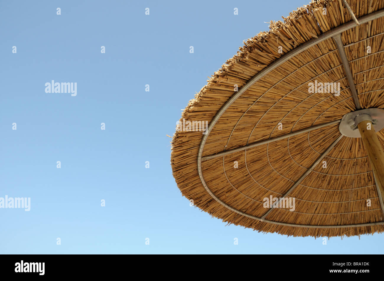Straw beach parasol umbrella and blue sky background Stock Photo - Alamy