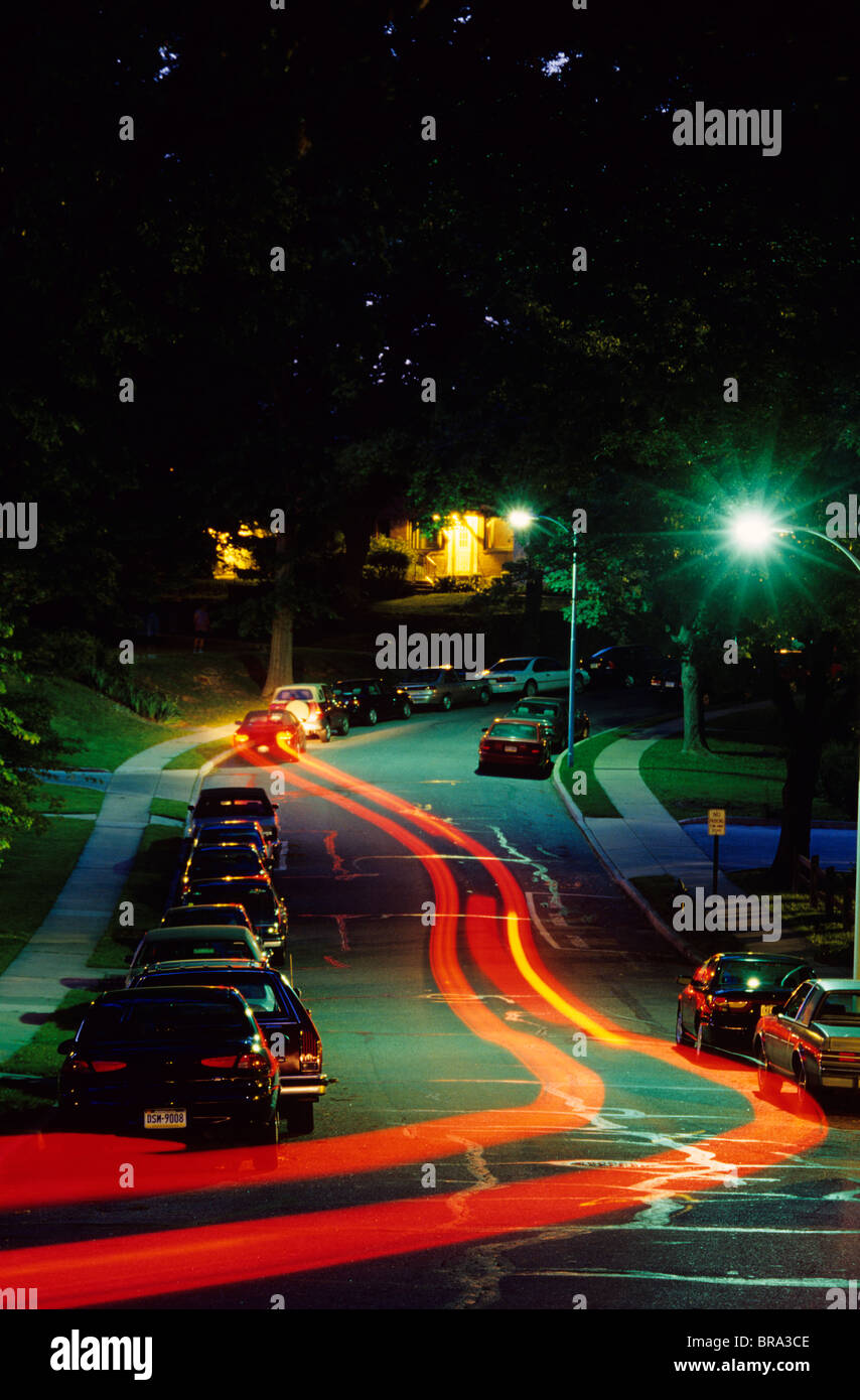 STREAKS OF LIGHT FROM CAR HEADLIGHTS ON RESIDENTAL STREET AT NIGHT ...