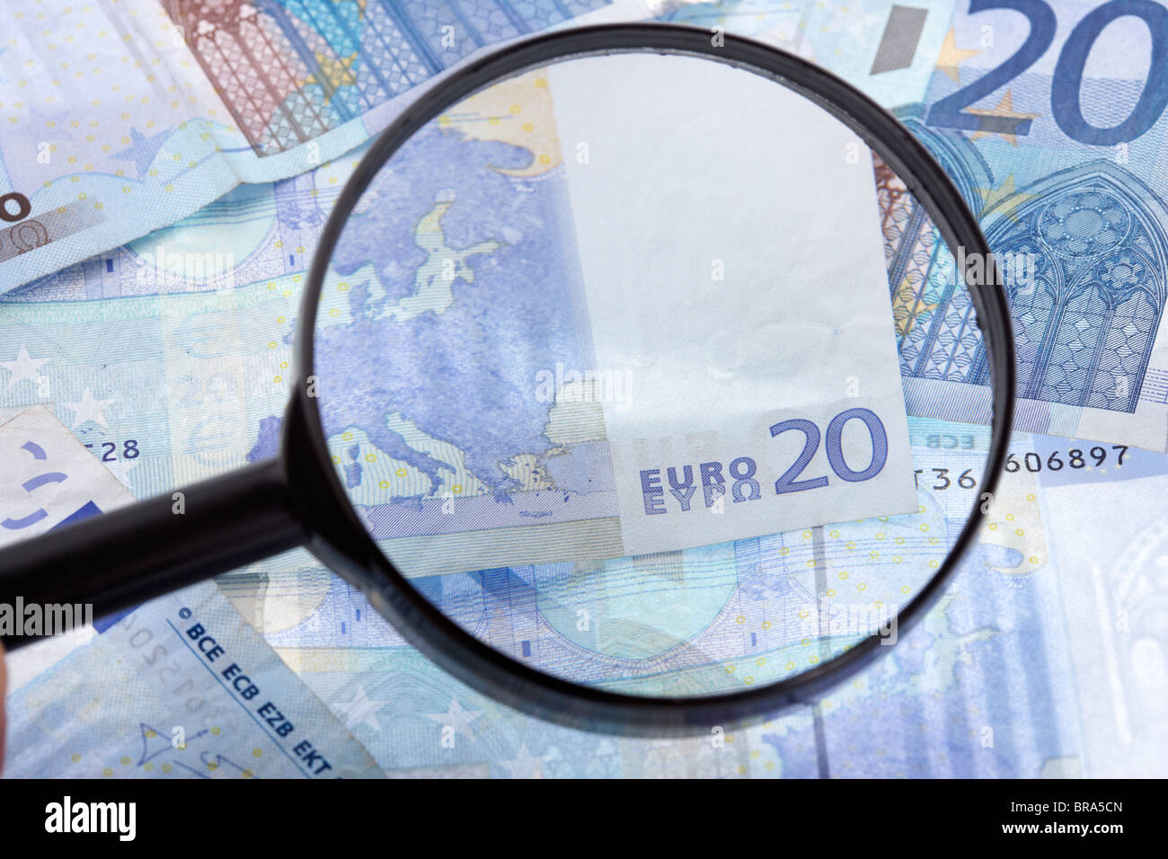 magnifying glass examining twenty euro notes Stock Photo - Alamy
