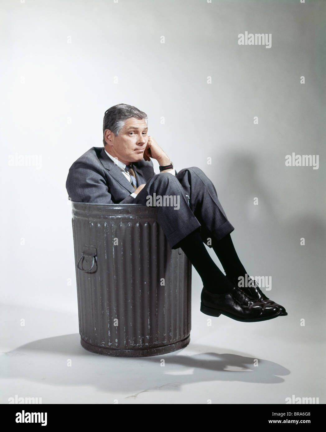 1960s SAD MAN IN BUSINESS SUIT SITTING IN TRASH GARBAGE CAN Stock Photo ...