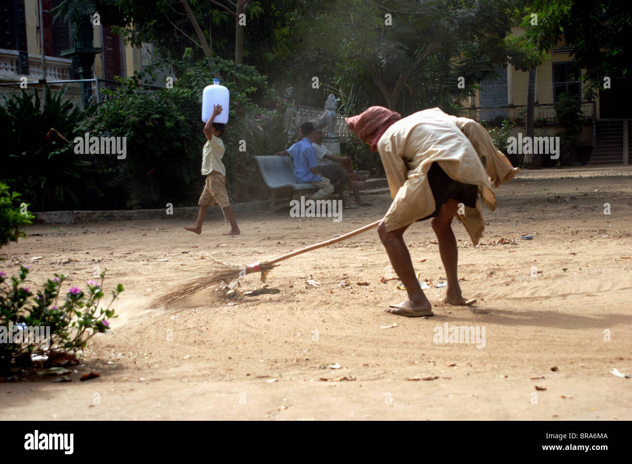 A young child laborer carries a bottle of water on his head while an ...