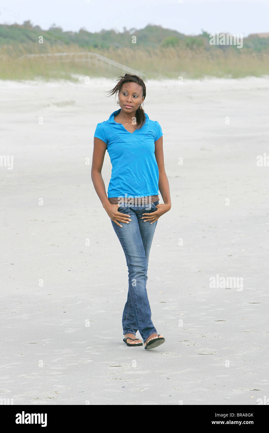 one thin African American woman model walking on the beach with a ...