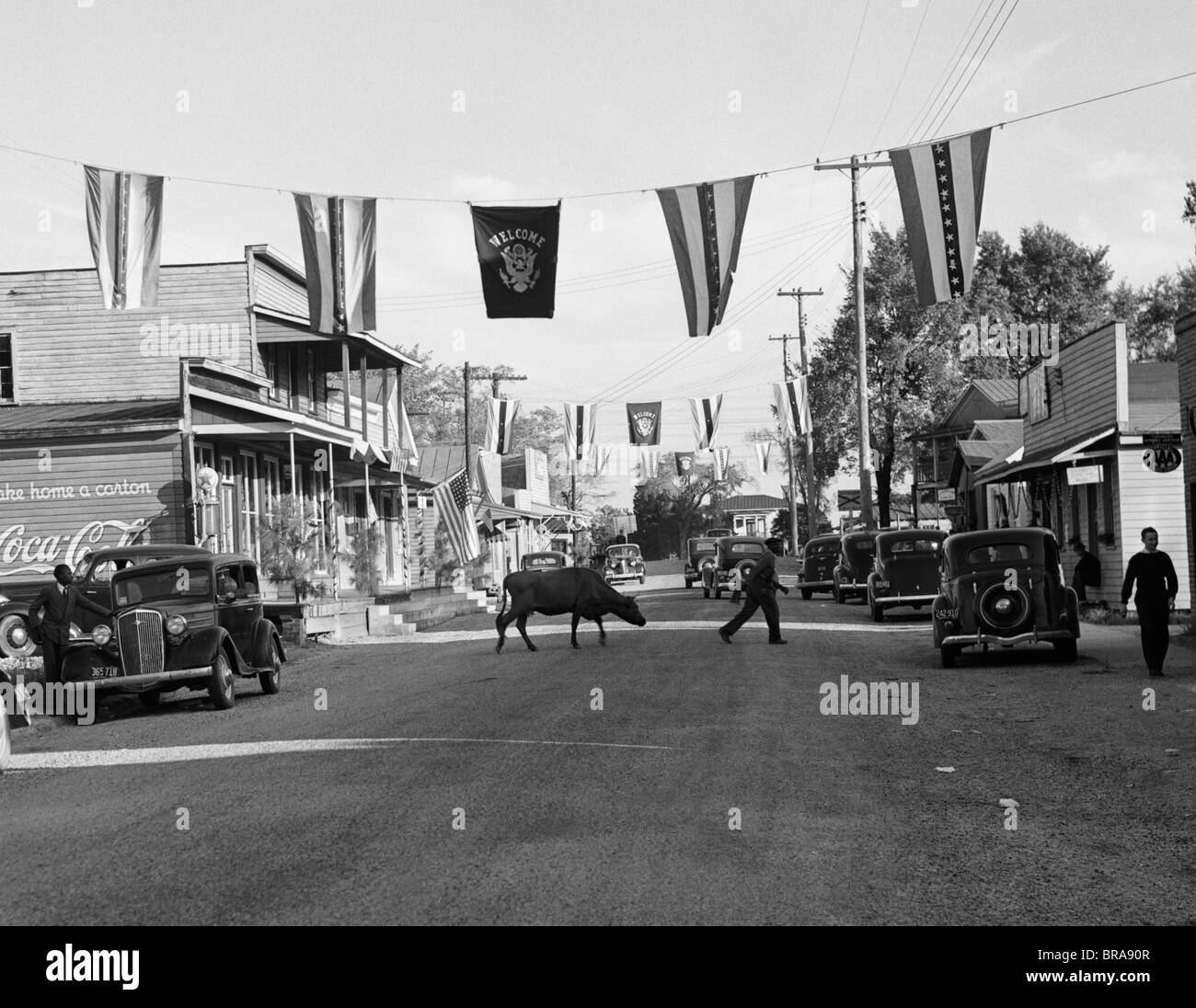 1930s MAIN STREET SMALL TOWN WITH FLAGS FLYING & COW CROSSING STREET ...