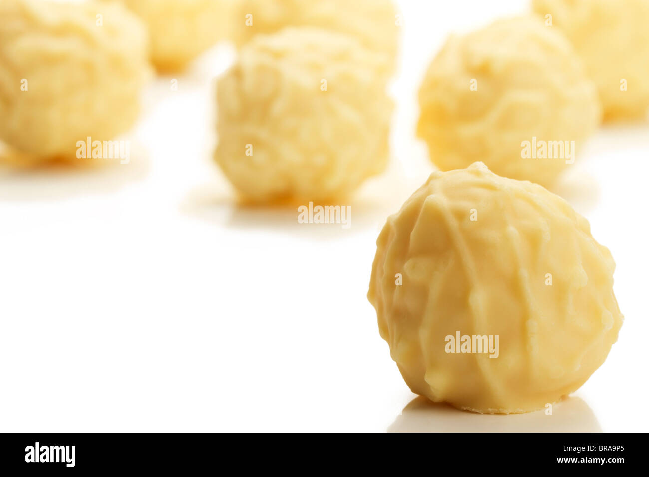 yellow truffle praline in front of many on white background Stock Photo ...