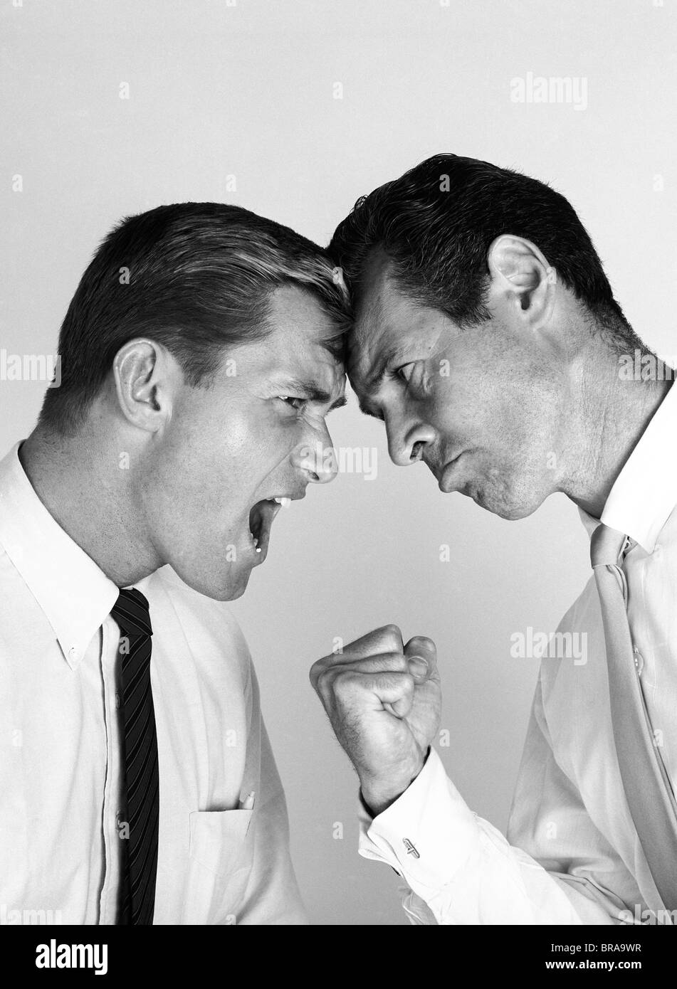 1960s PORTRAIT OF TWO BUSINESSMEN HEAD TO HEAD FIGHTING FISTS RAISED ...
