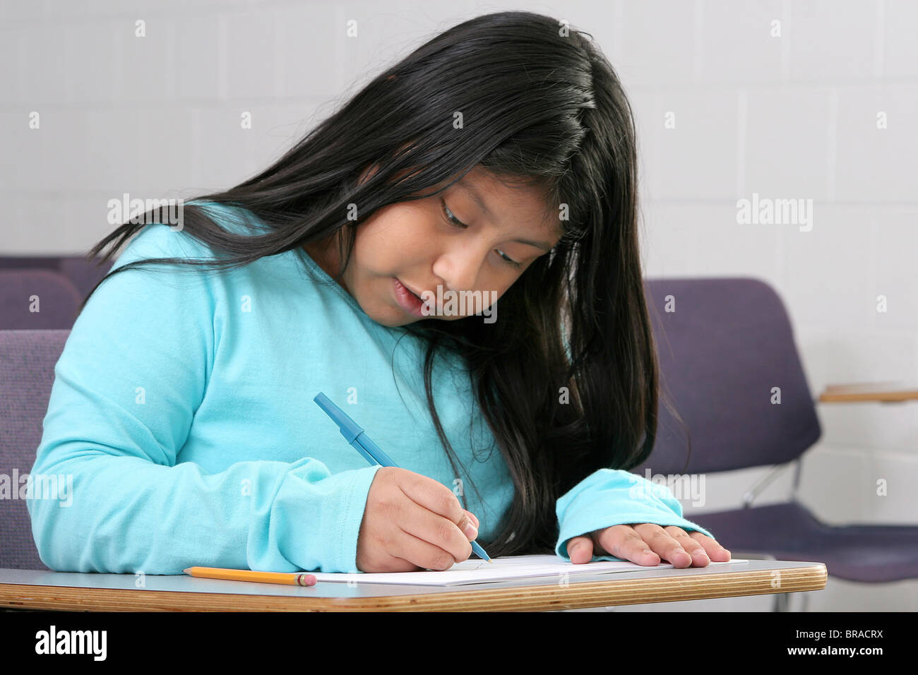 one young girl student writing in a classroom Stock Photo - Alamy