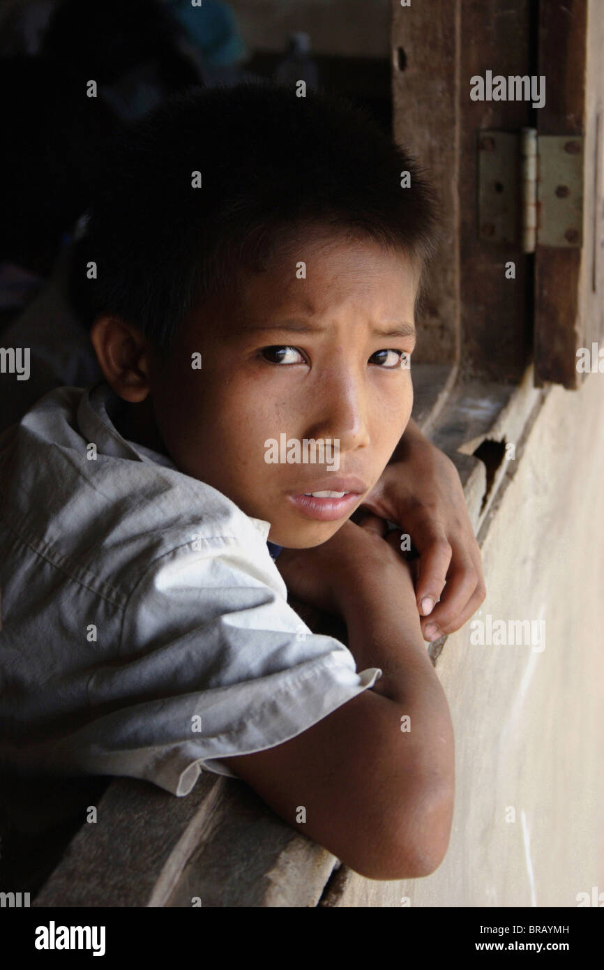 A 9 year old boy student is looking out of a schoolhouse classroom ...
