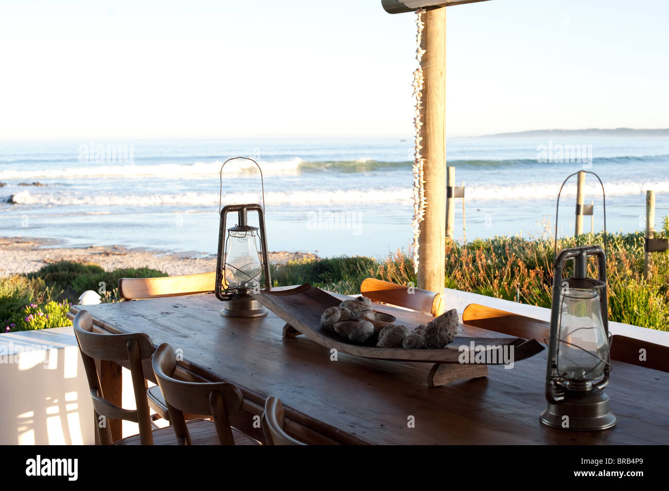 Dining table on verandah overlooking ocean with waves Stock Photo - Alamy