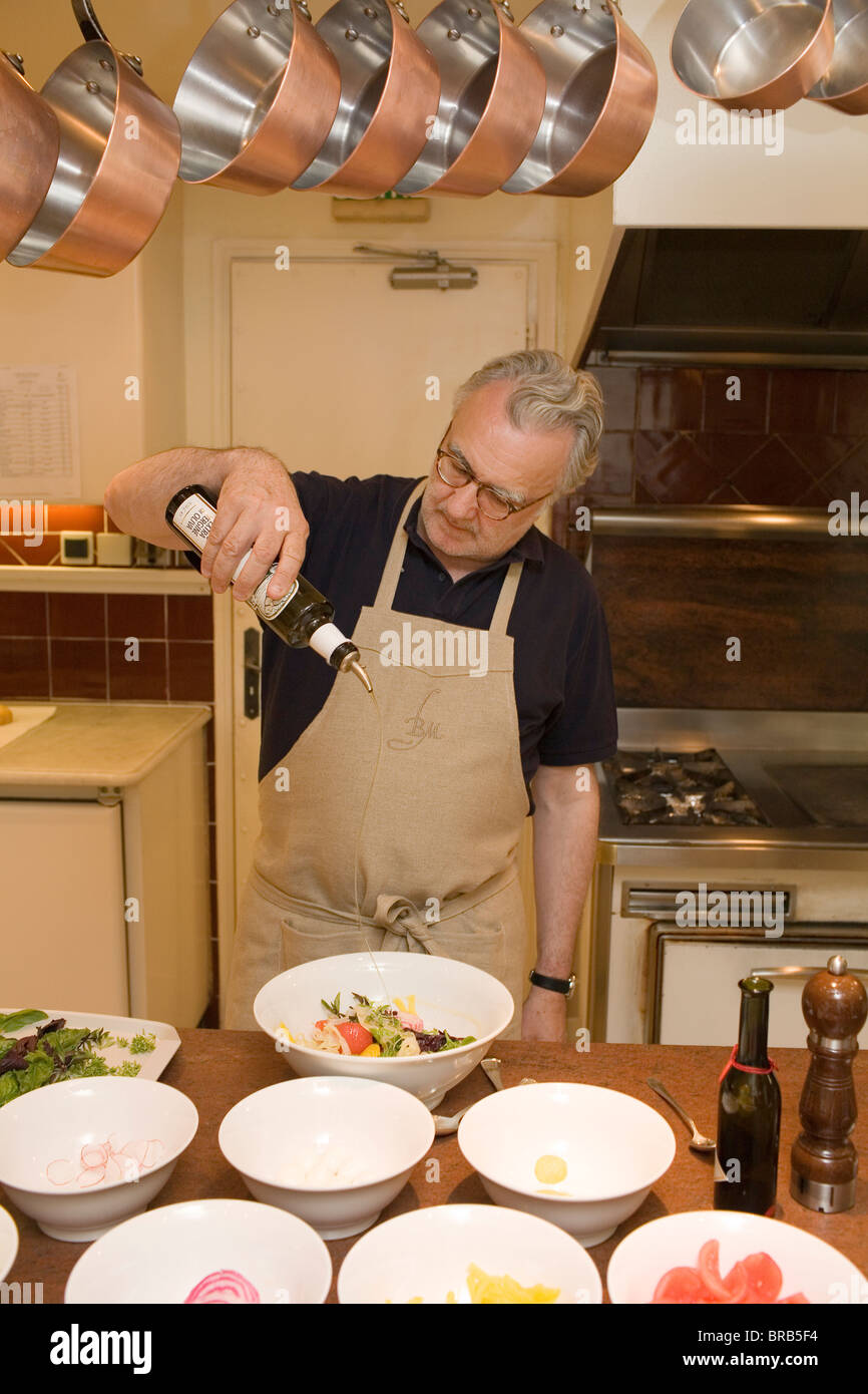 French Chef Alain Ducasse pours olive oil into a bowl of salad Stock ...