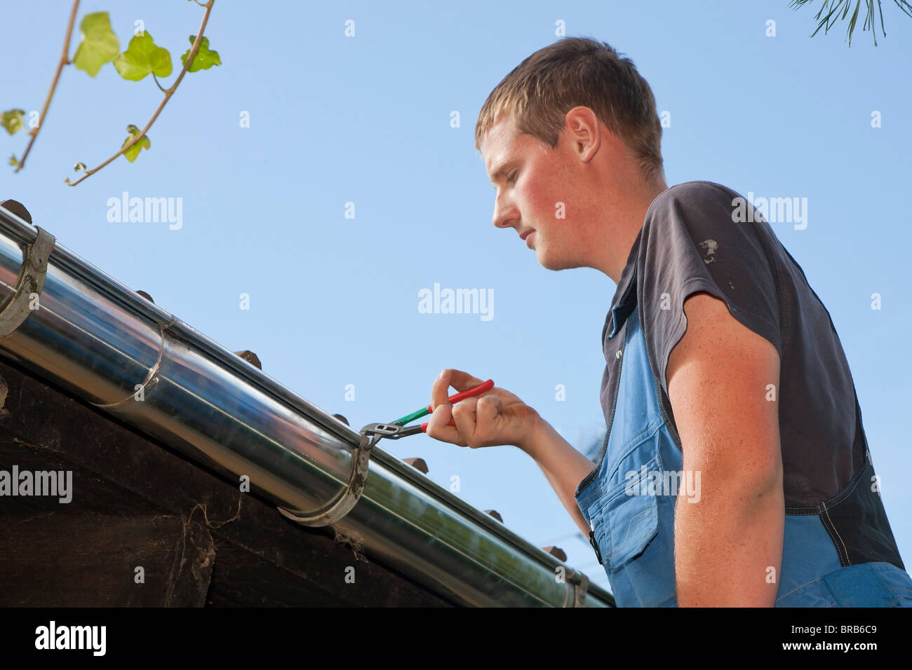 Young plumber fasten a gutter Stock Photo - Alamy