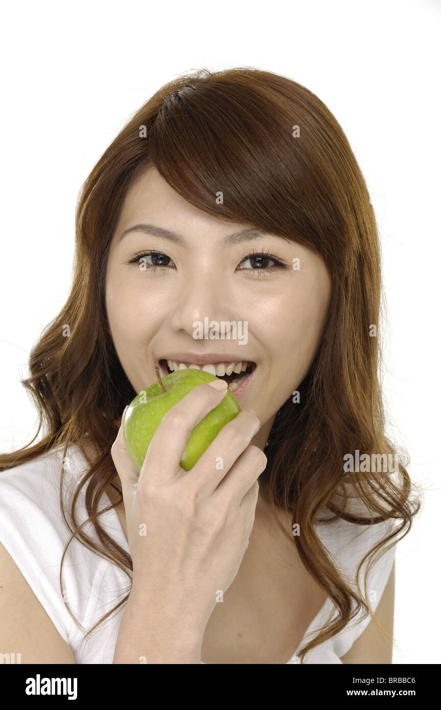 Young beautiful woman eating green apple isolated over white background ...