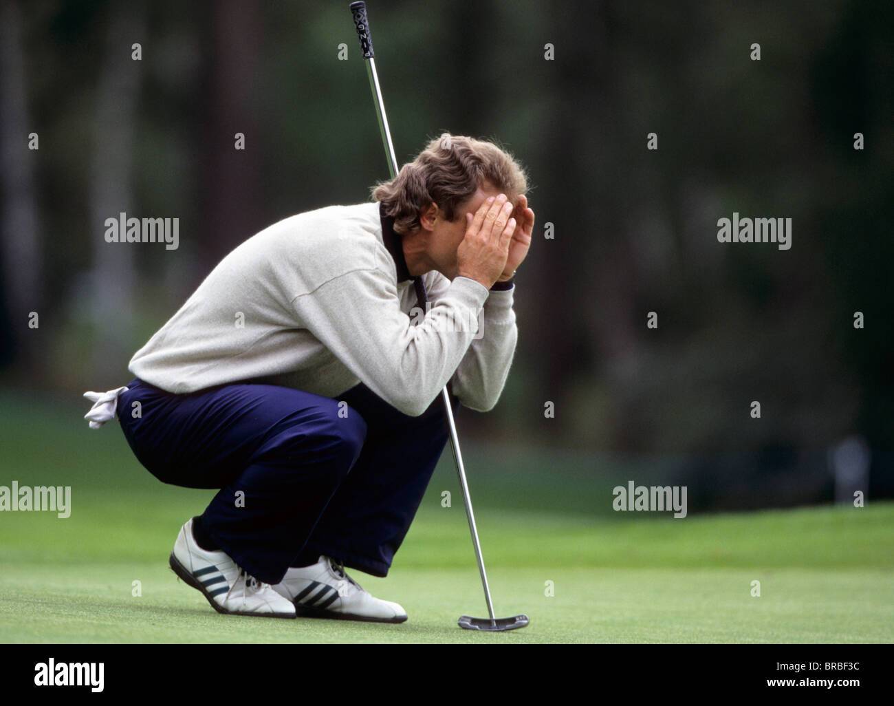 Man crouching while golfing Stock Photo - Alamy