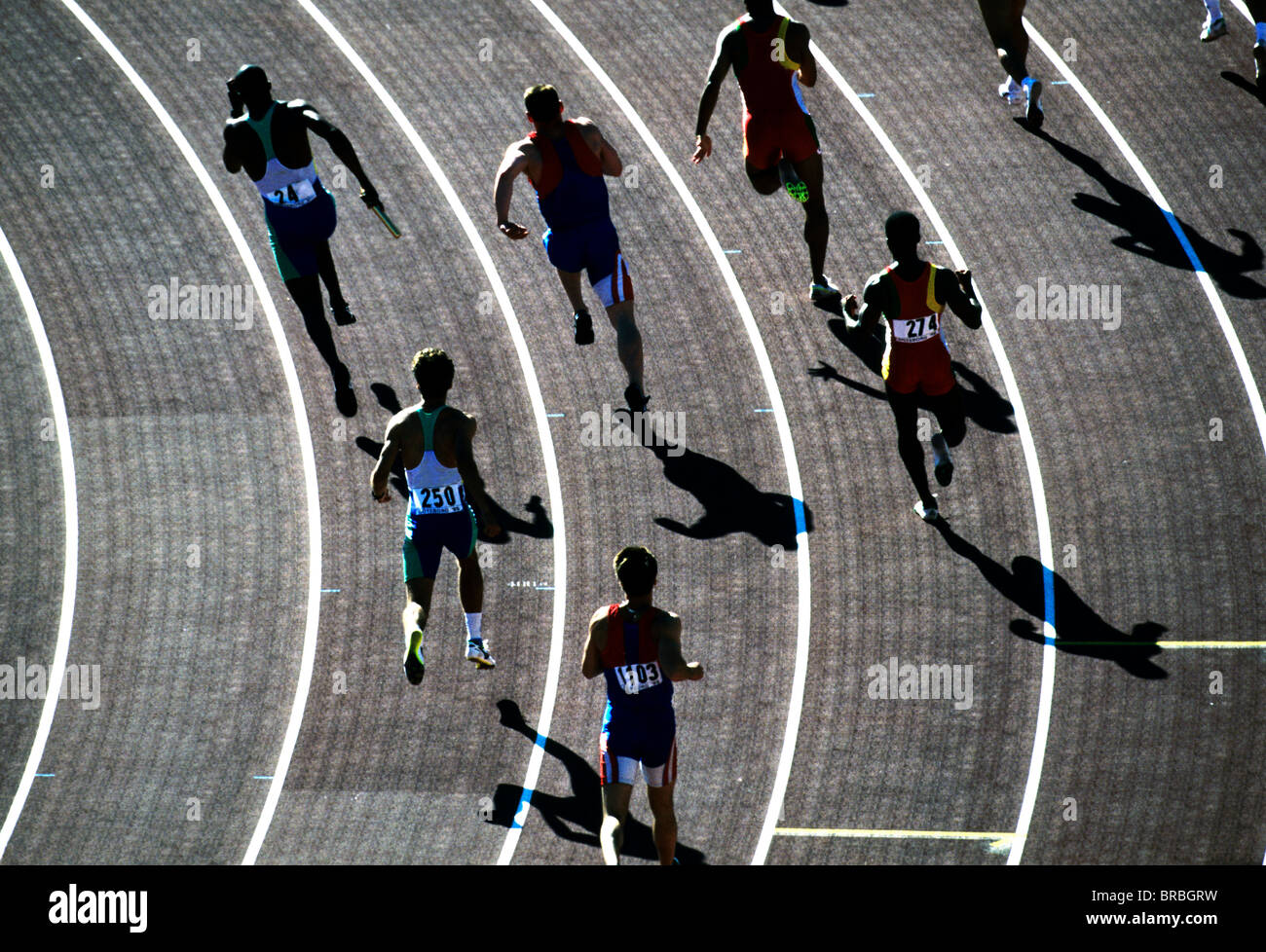Relay runners passing the batons at the bend of a race track Stock ...