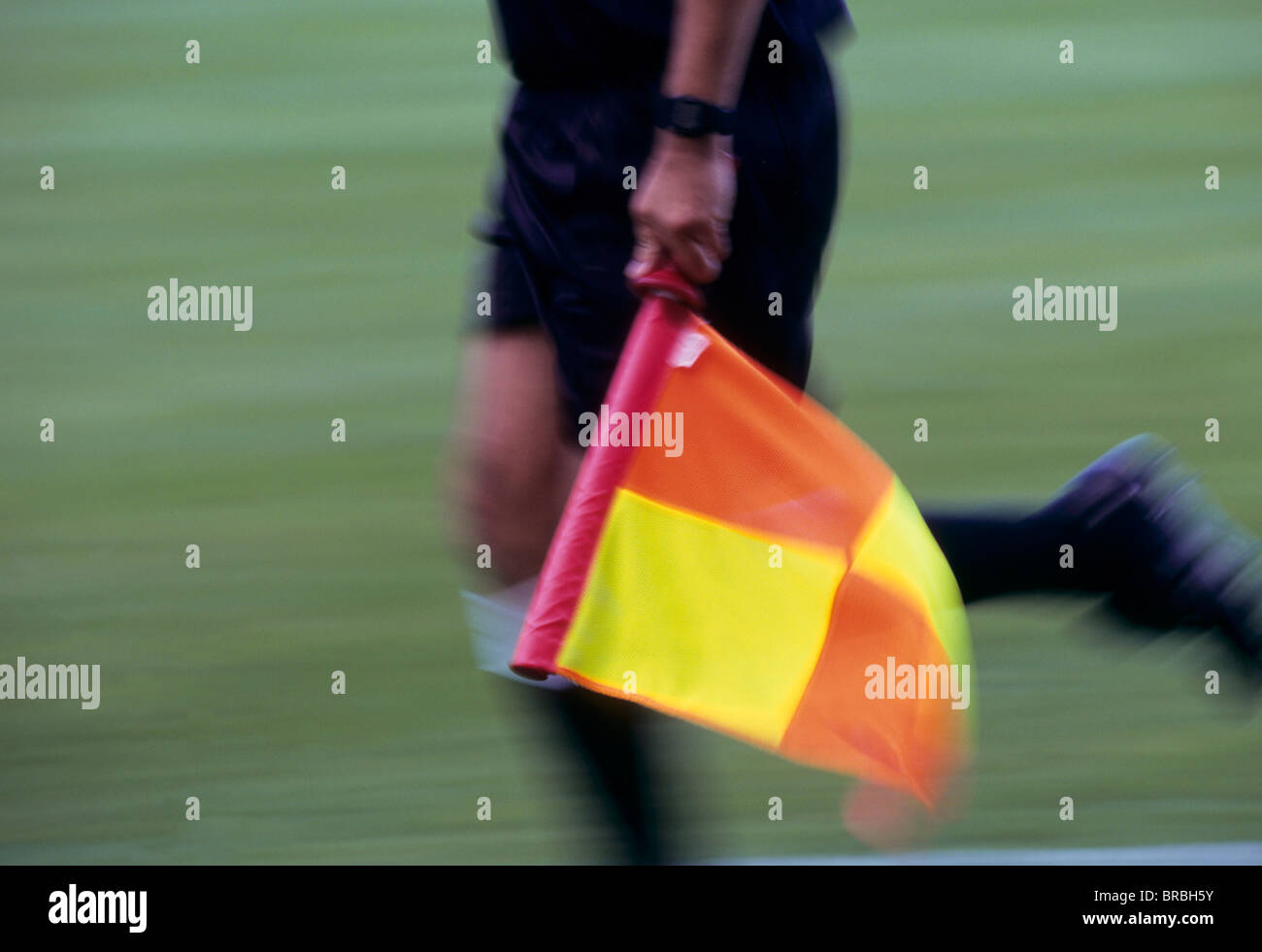 Linesman running whilst holding a flag Stock Photo - Alamy