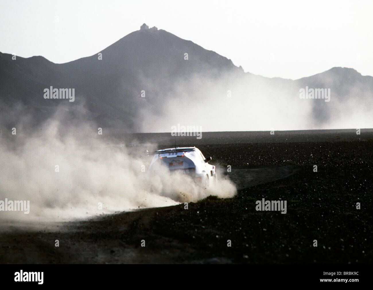 Rally car traverses across a desert course billowing dust behind Stock ...