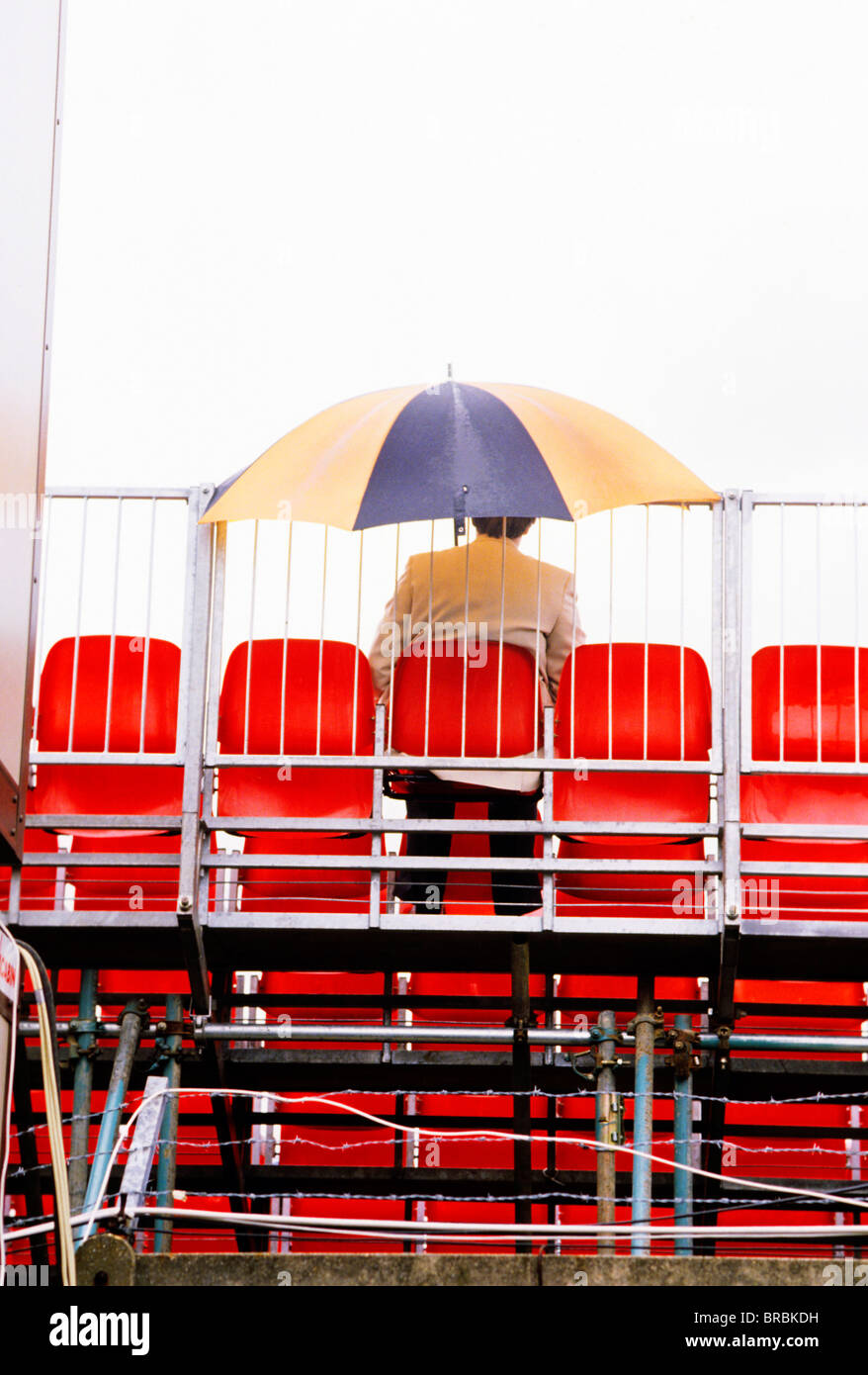 Spectator sitting in stands with an umbrella Stock Photo - Alamy