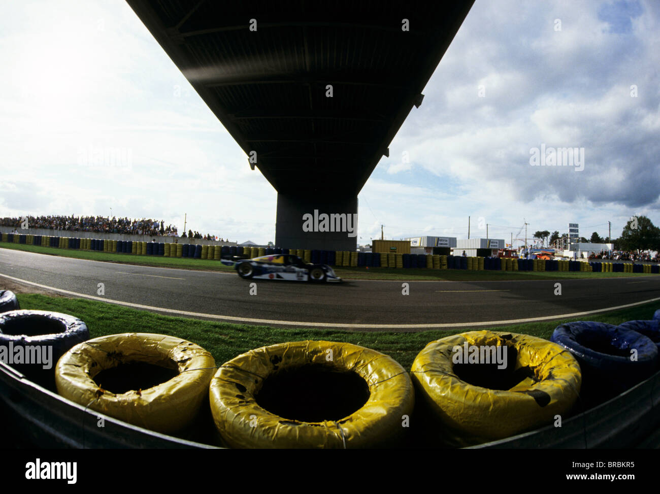 Race car driving under a bridge on track Stock Photo - Alamy