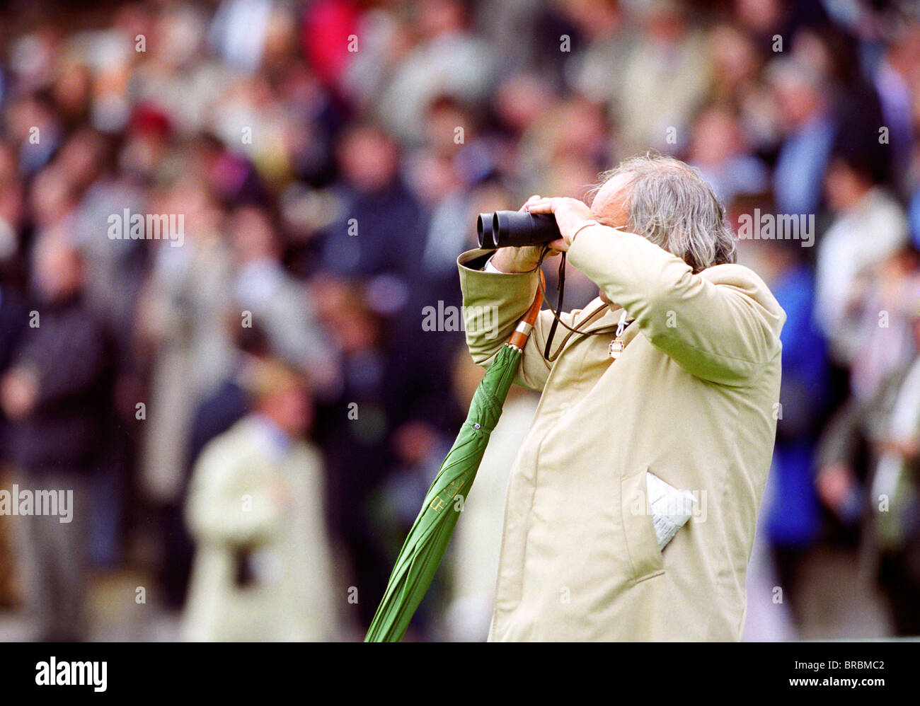 Horse racing spectator uses binoculars to keep track of horse race ...
