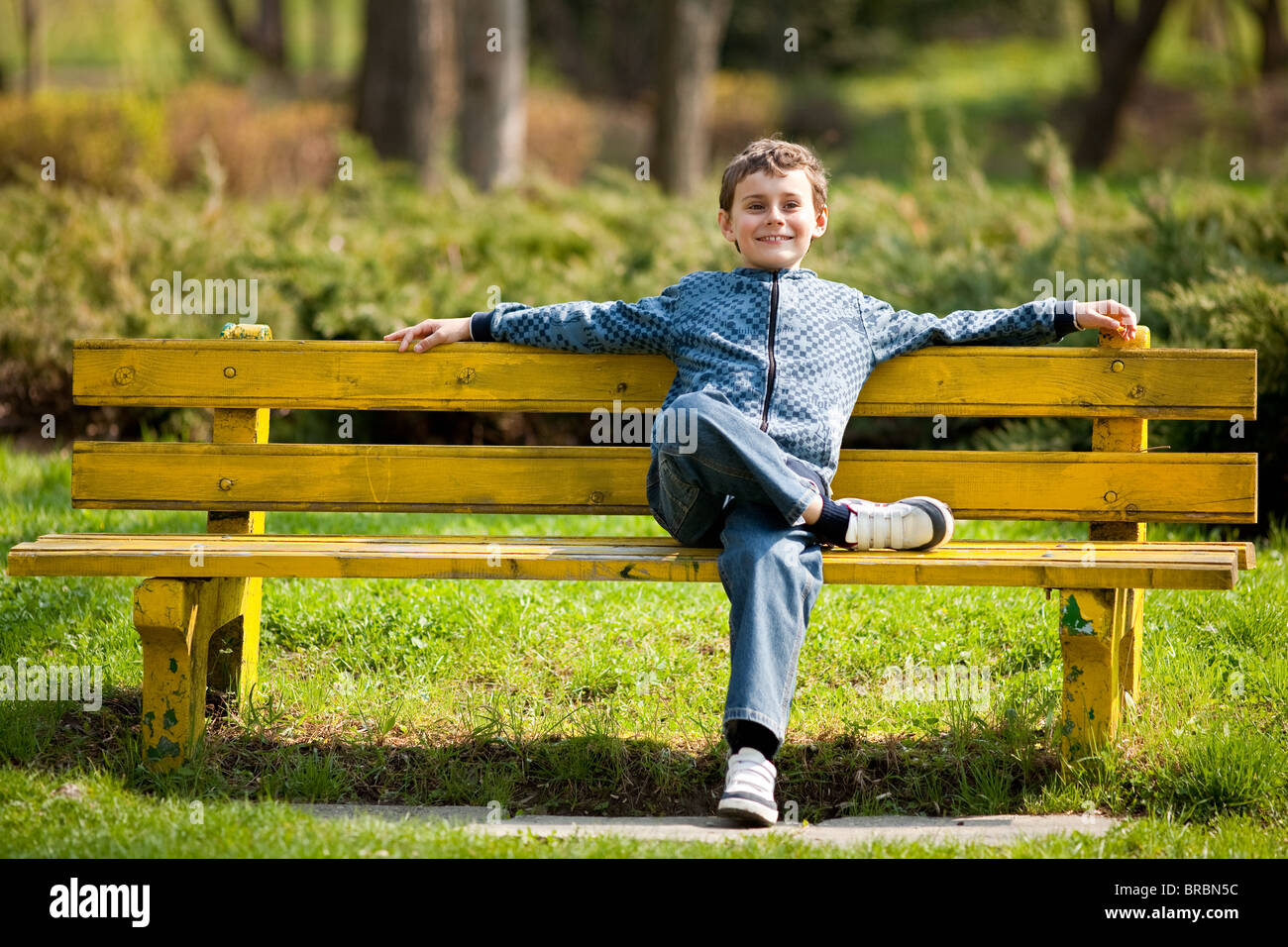 Cute schoolboy relaxing sitting on bench in a park Stock Photo - Alamy