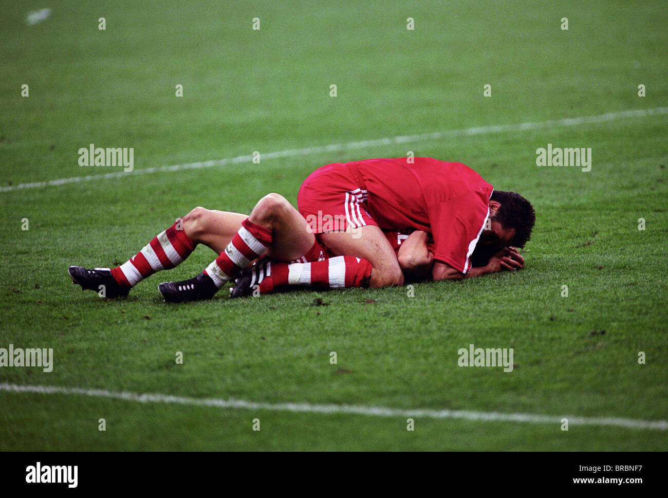 Two footballers embrace as their team scores a goal Stock Photo - Alamy
