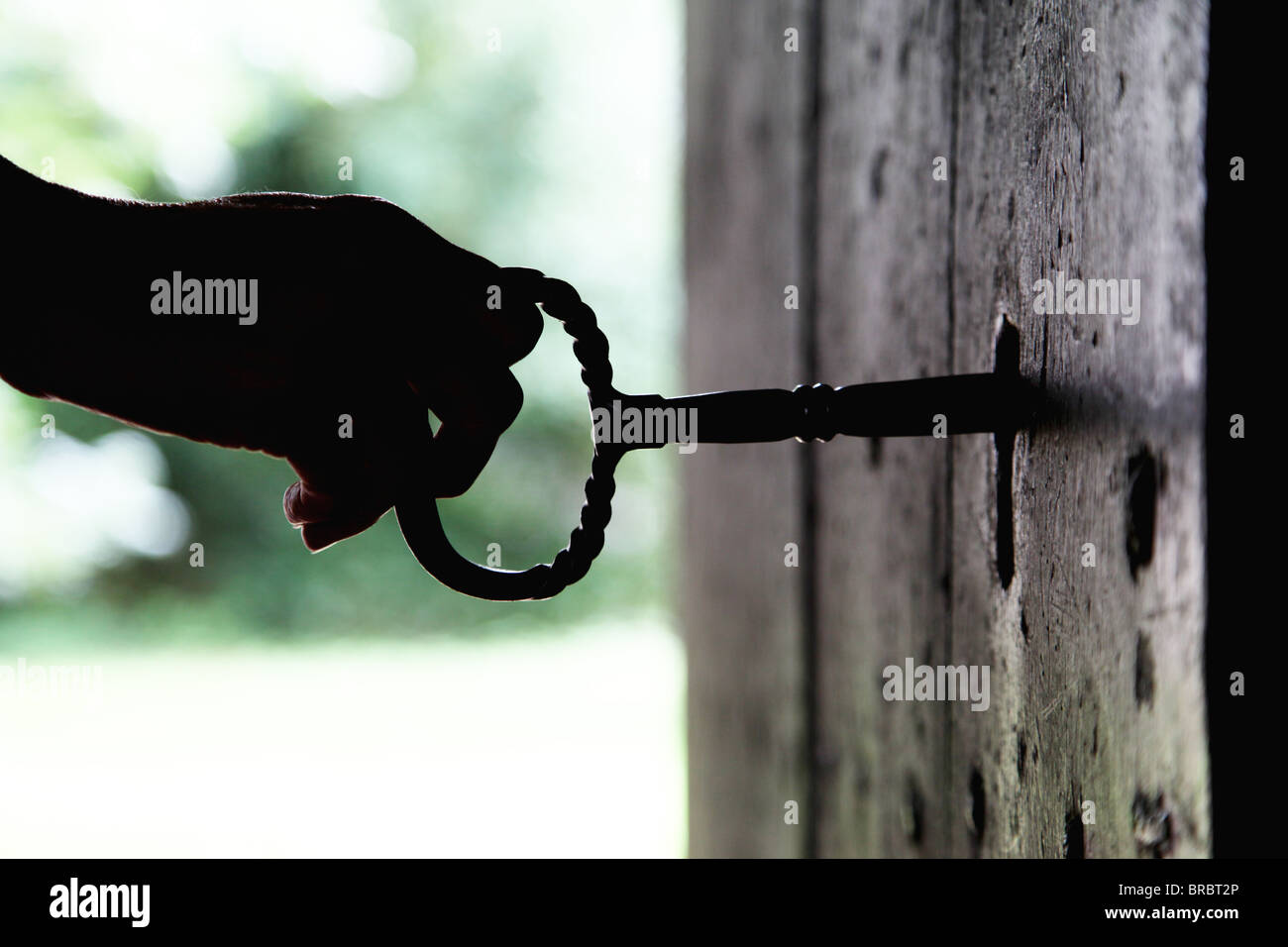 Silhouette of a woman's hand turning a giant key in an ancient wooden ...