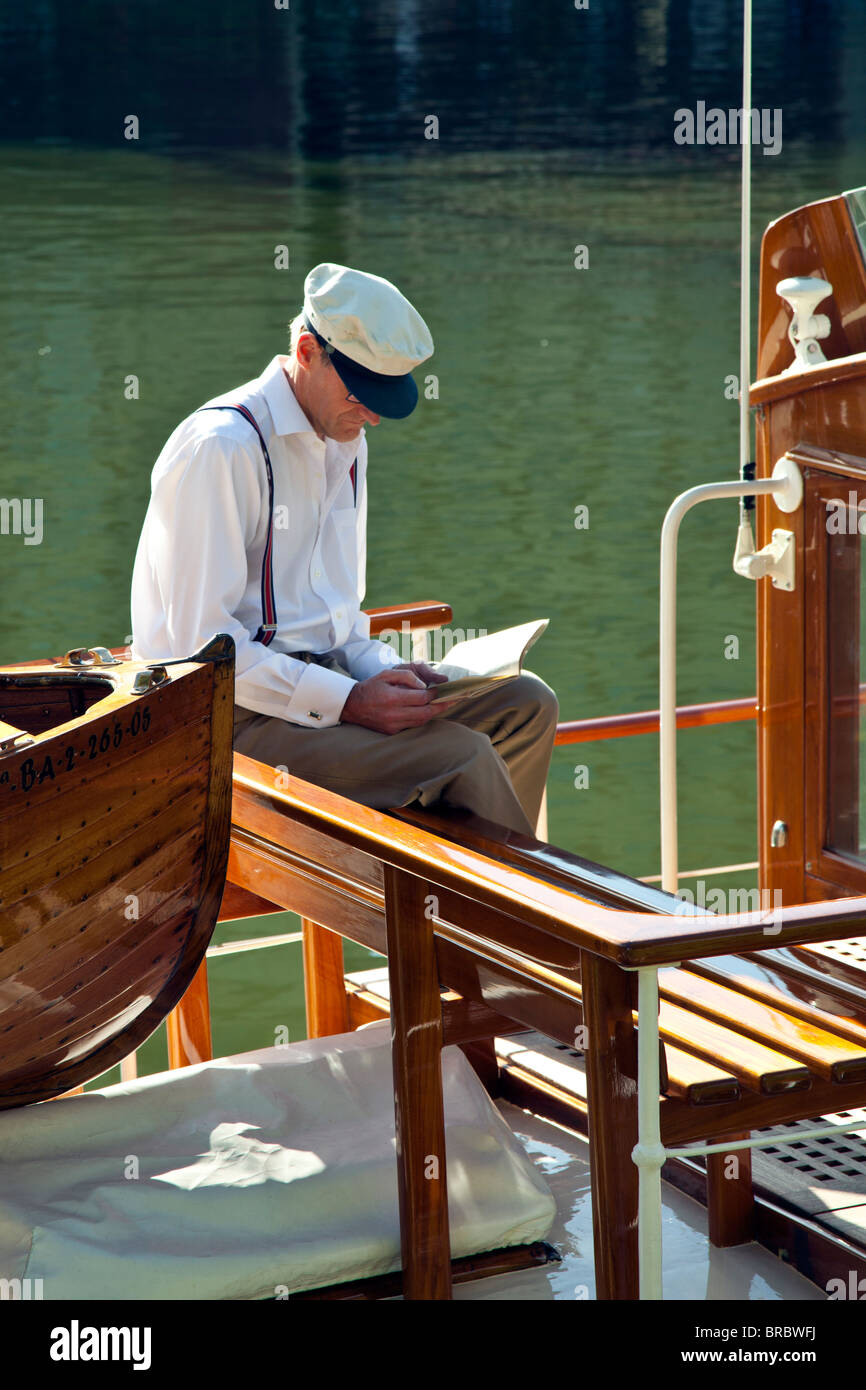 Gentleman reading a book on a yacht in St Katherine’s Dock, London, UK ...
